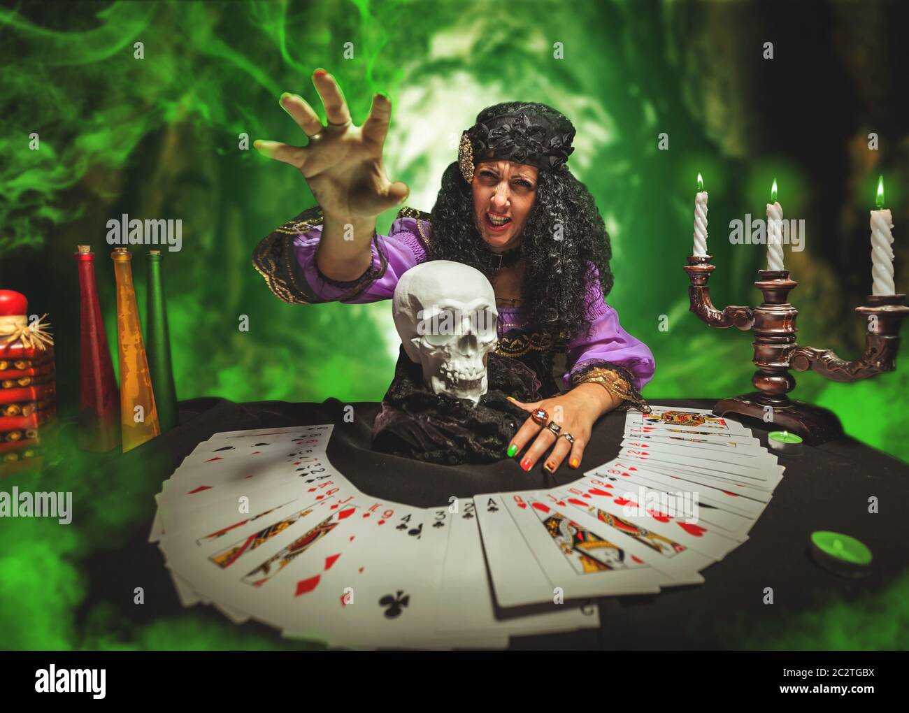 Strong sorceress practises witchcraft using pack of cards and the skull ...