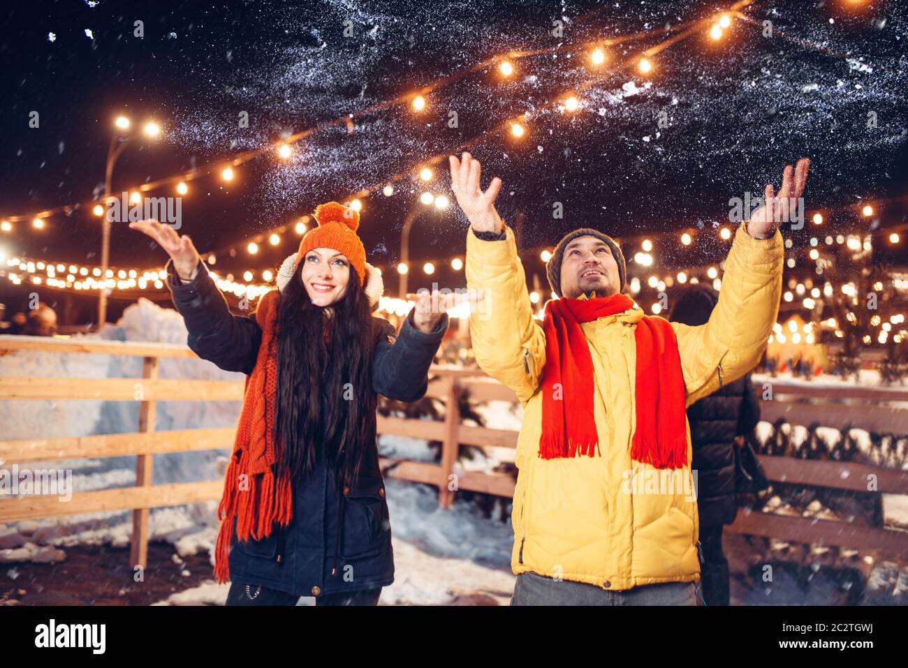 Winter evening, playful love couple throw snow up. Man and woman having ...