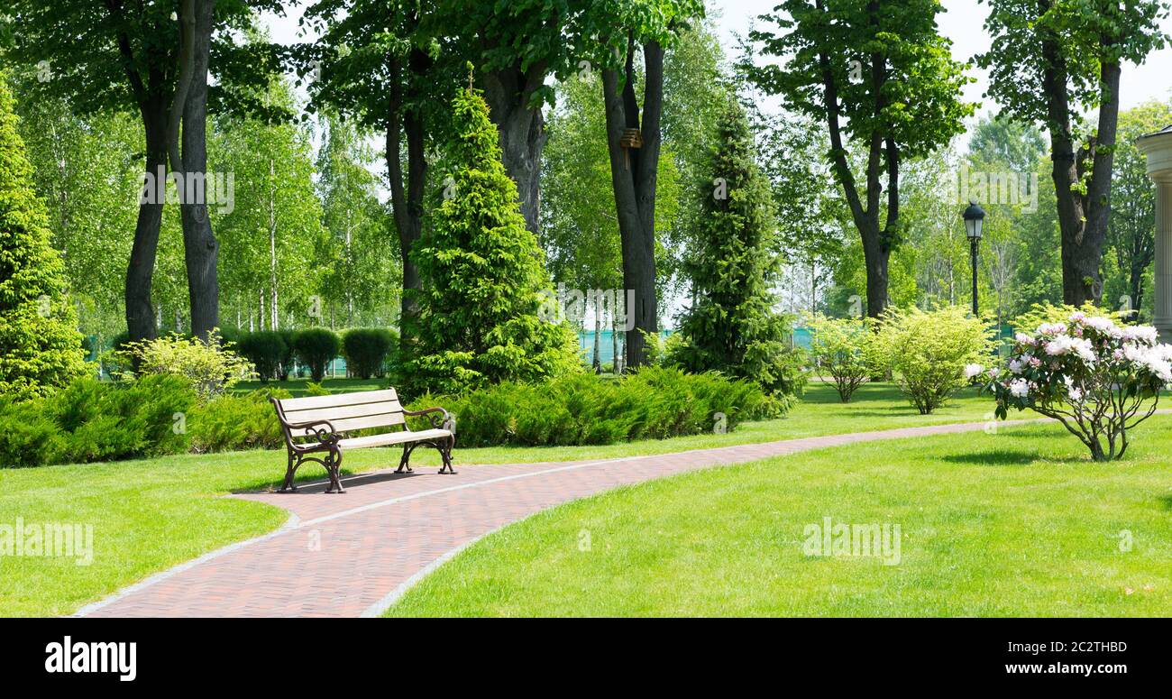 Long stone pavement with bench in the green park Stock Photo - Alamy