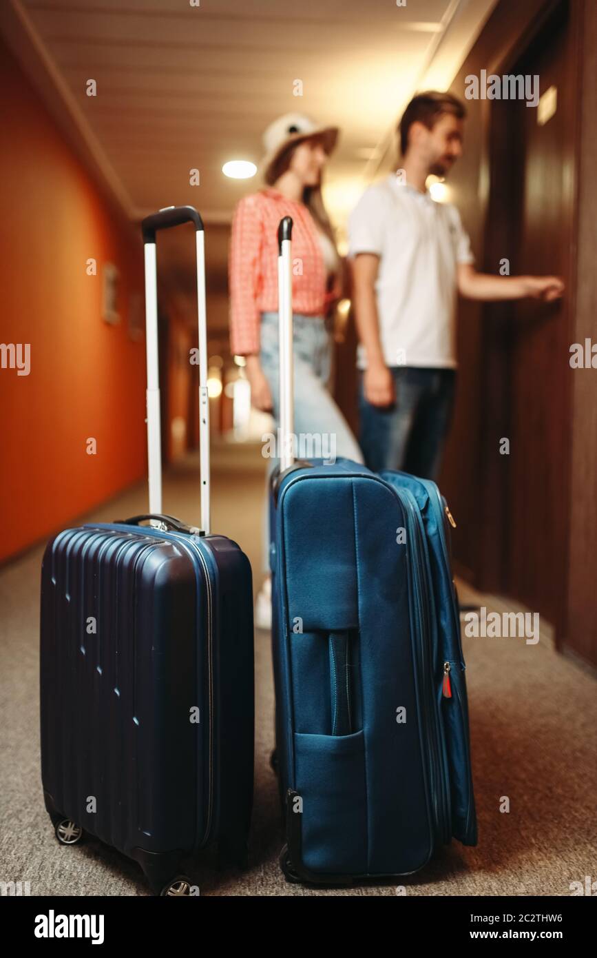 Suitcases in hotel hallway, couple open the door of the hotel room on ...