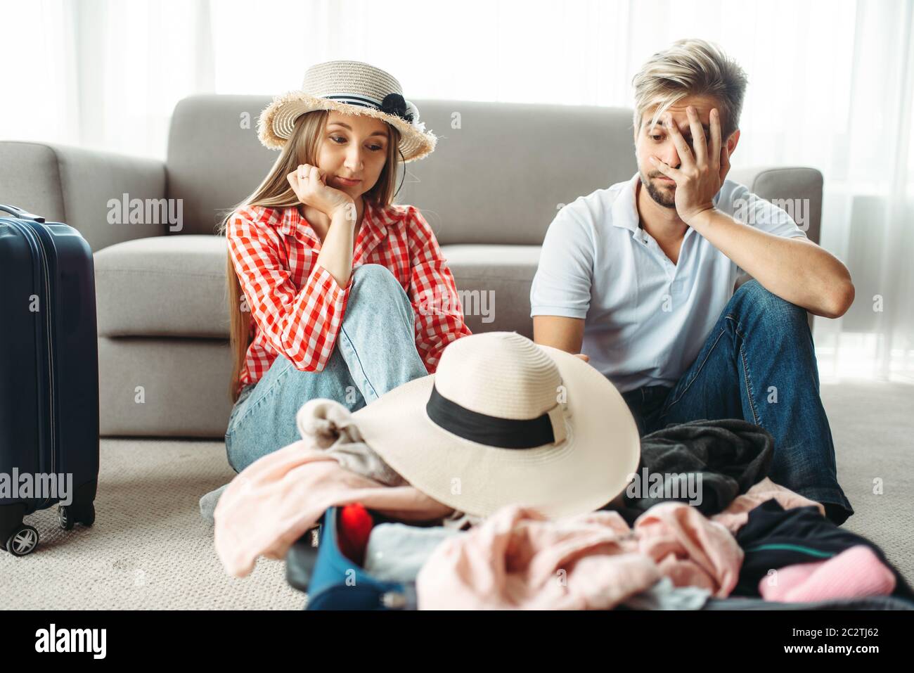 Tired couple packing their overloaded bag for vacation, overflowing ...