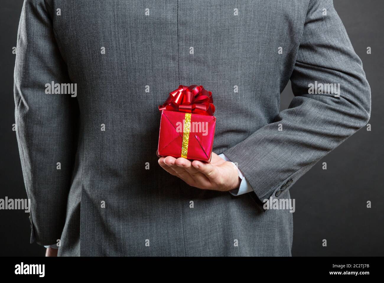 Businessman hiding a gift behind his back Stock Photo - Alamy