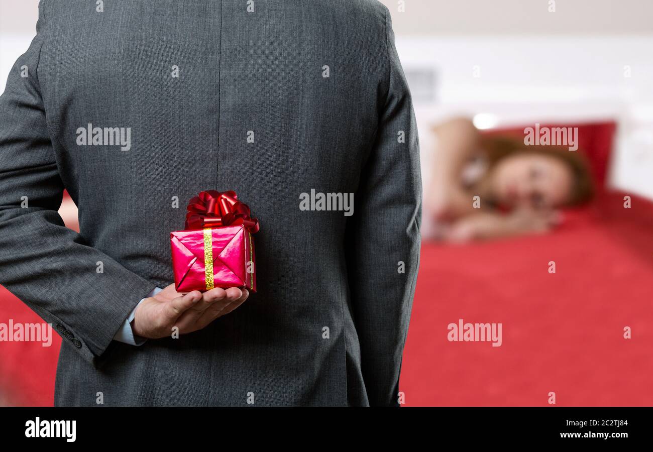 Businessman hiding a gift for his wife behind his back Stock Photo - Alamy
