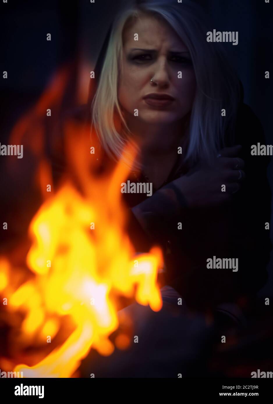 Blonde woman sitting in front of the fire Stock Photo - Alamy