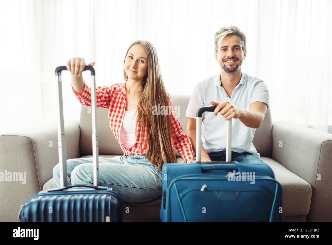 Young couple with suitcases sitting on the couch. Fees on journey ...