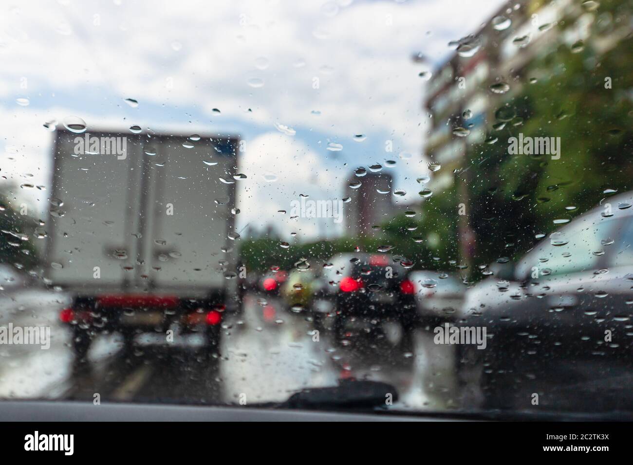 Traffic in rainy day with road view through car window with rain drops ...