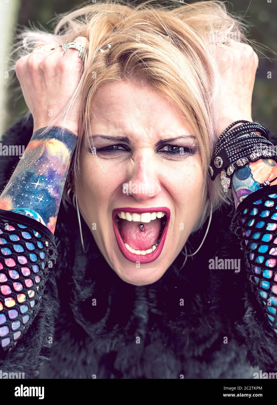 Screaming angry blonde woman with piercings and tattoos Stock Photo - Alamy