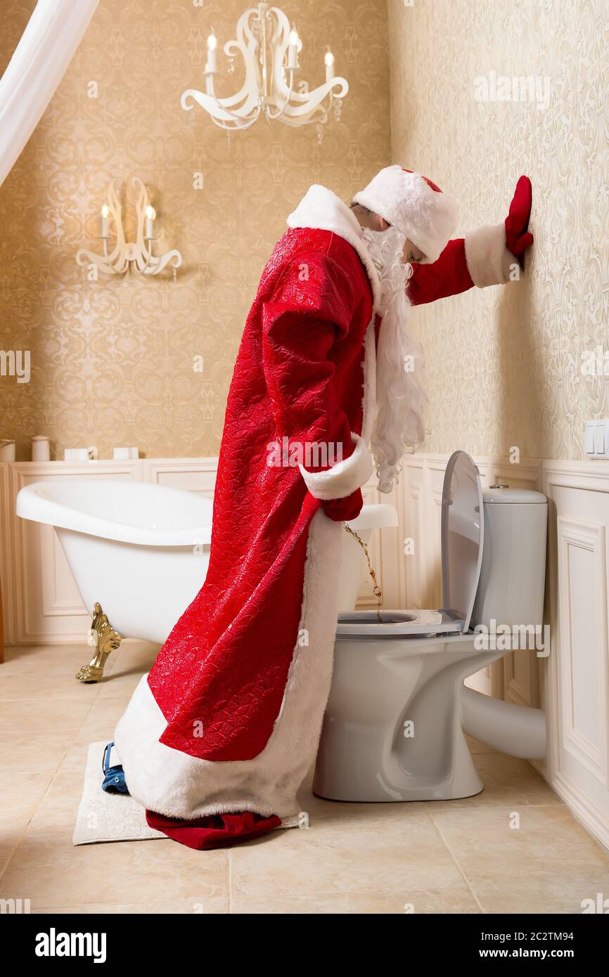 Funny drunk Santa Claus in red costume peeing in the toilet. Father ...