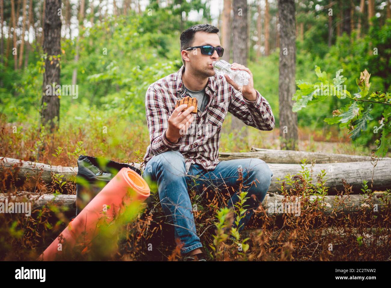 Fast food theme snack on nature. Caucasian man eating a sandwich and ...