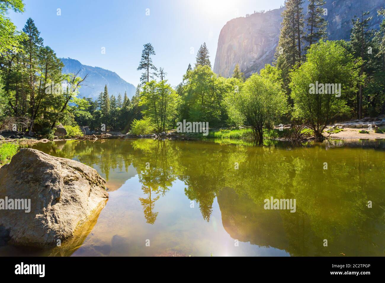 Clear water and evergreen pine forest surrounded by granite mountains ...