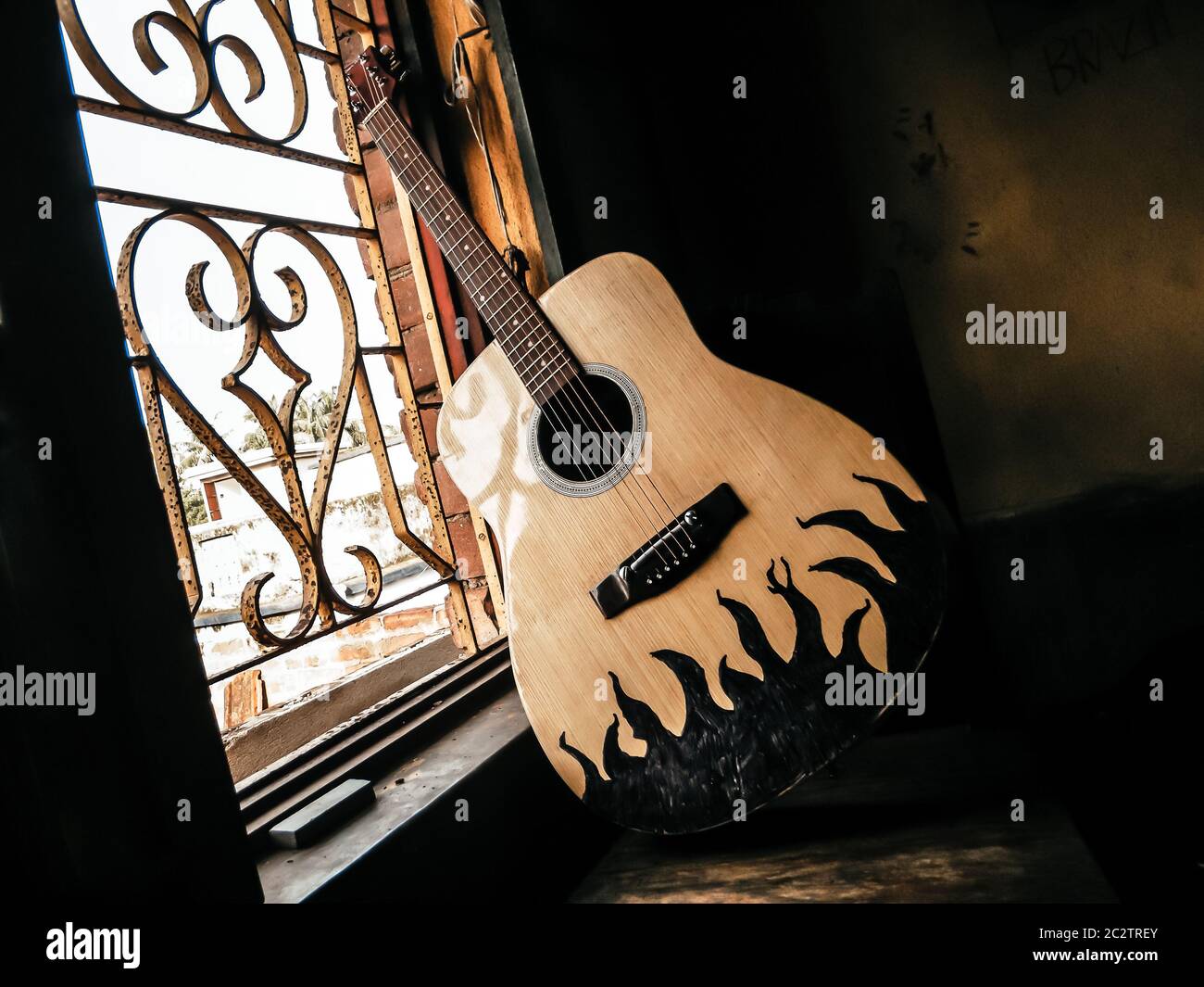 An acoustic guitar placed next to the old vintage window with soft ...