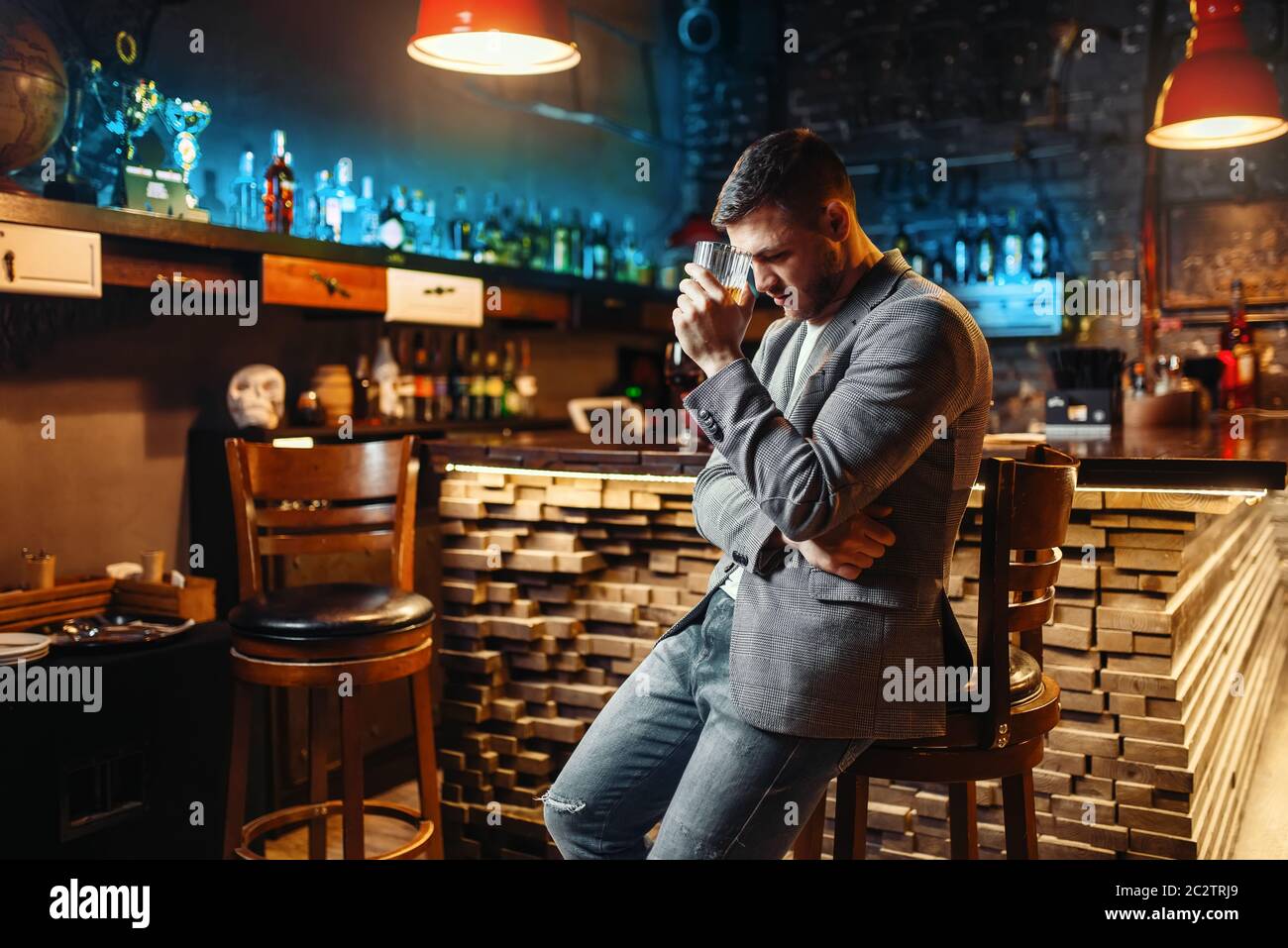 Sad man with glass of alcoholic beverage at wooden bar counter. Tired ...