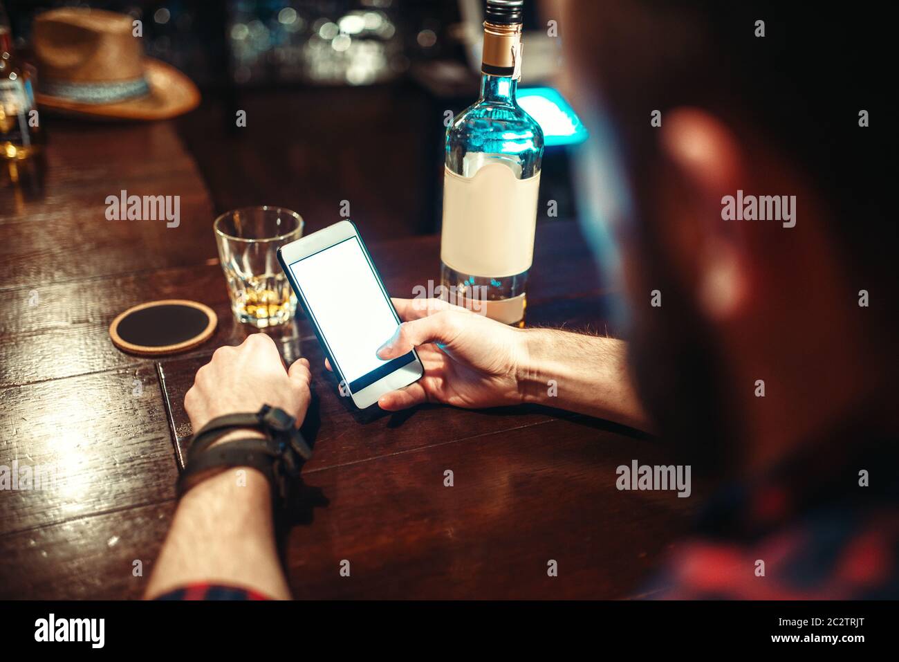 Male person with mobile phone sitting at the bar counter, relaxation ...