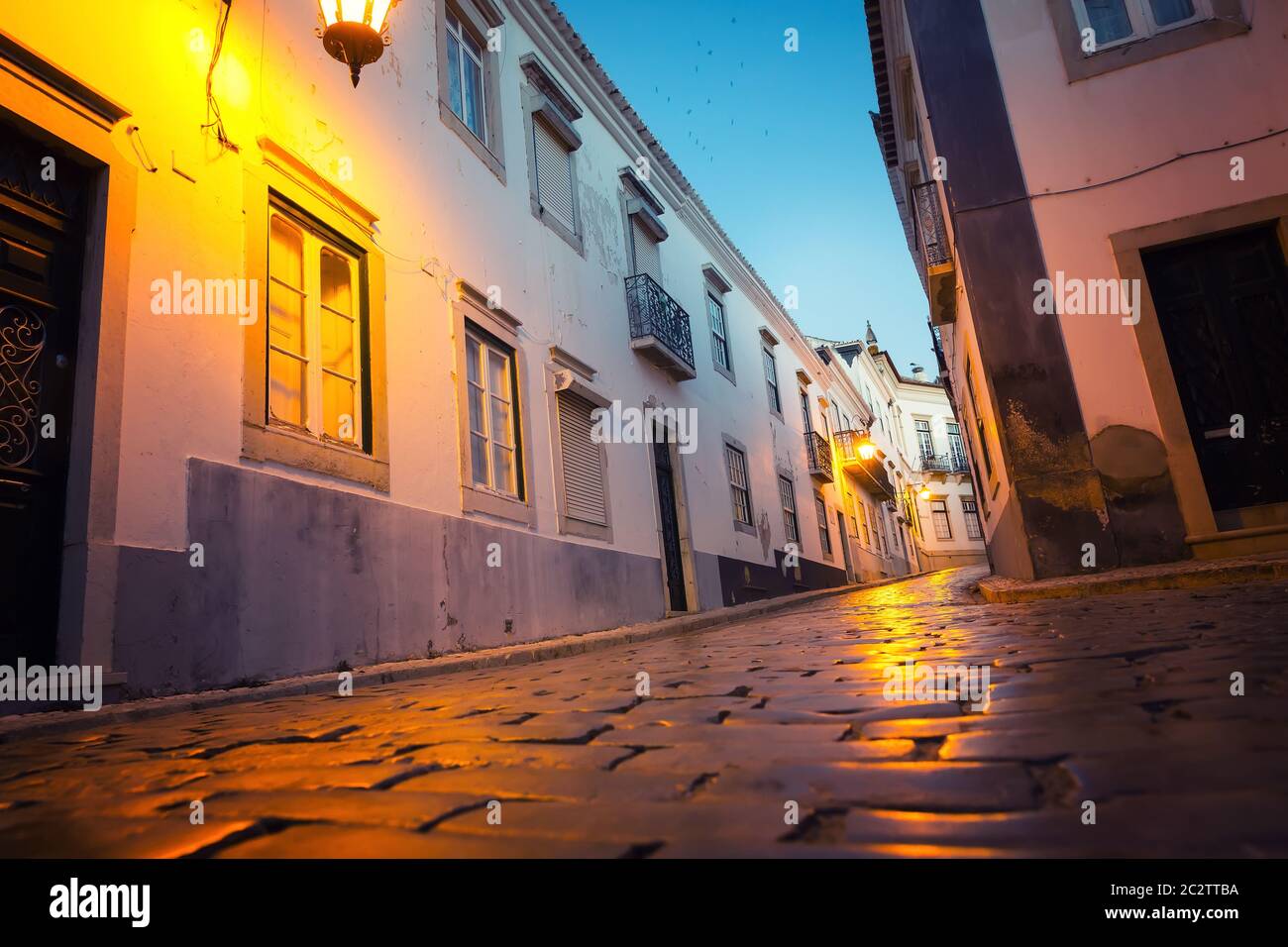 Narrow european street with paved road in the evening, buildings with ...