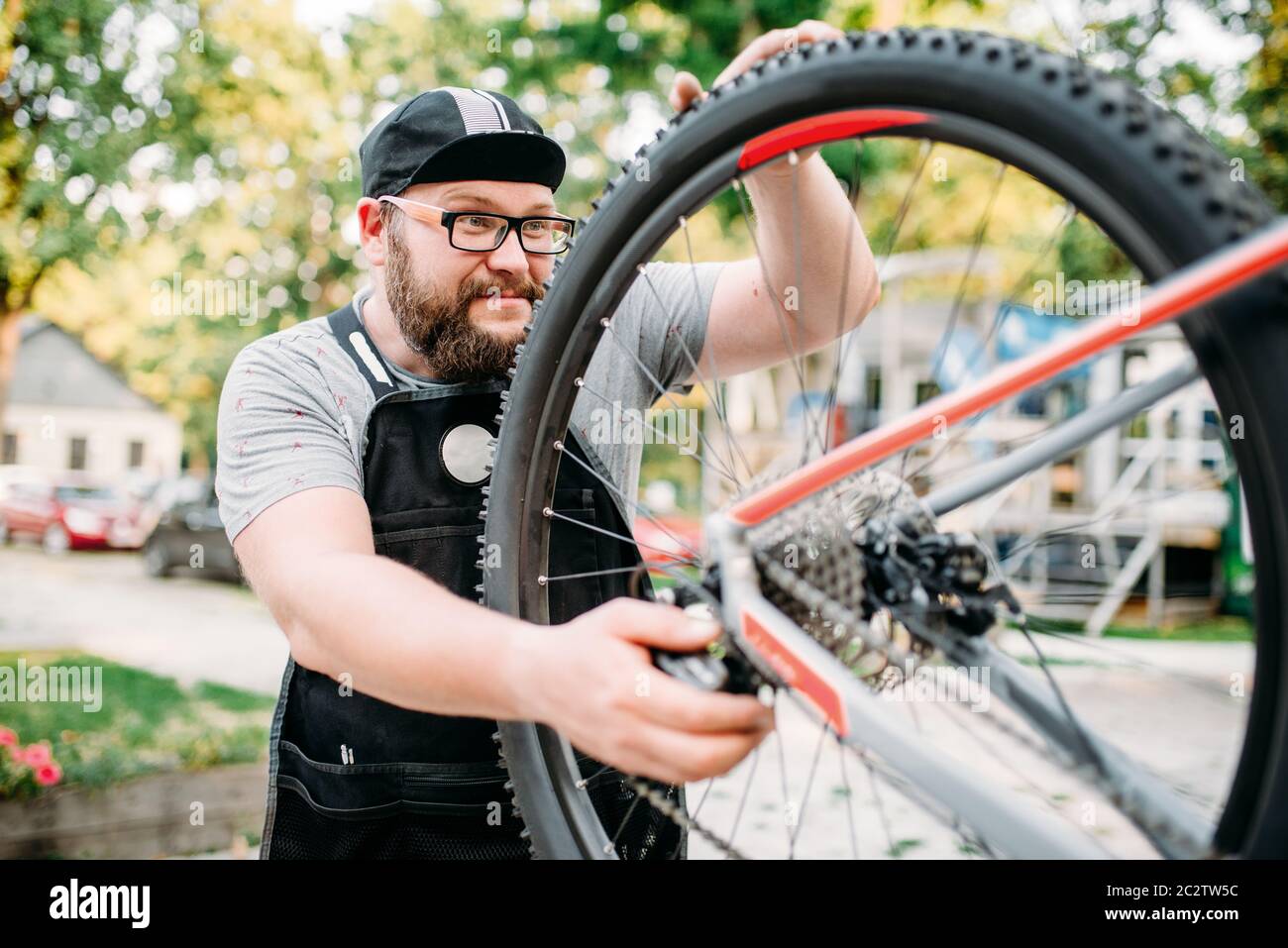 Bicycle repairman works with bike wheel, cycle workshop outdoor ...