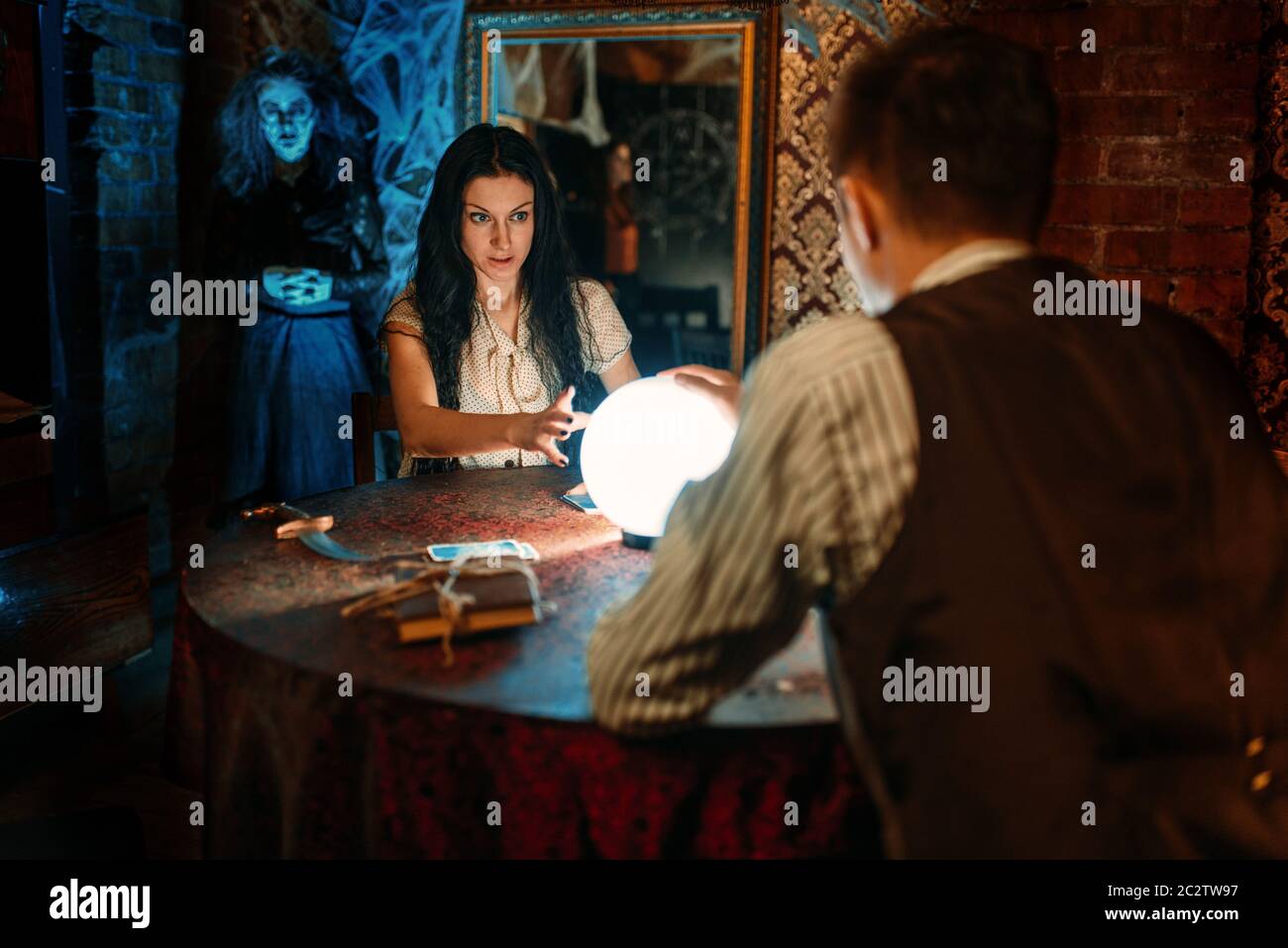 Young couple at the table with crystal ball on spiritual seance, scary ...