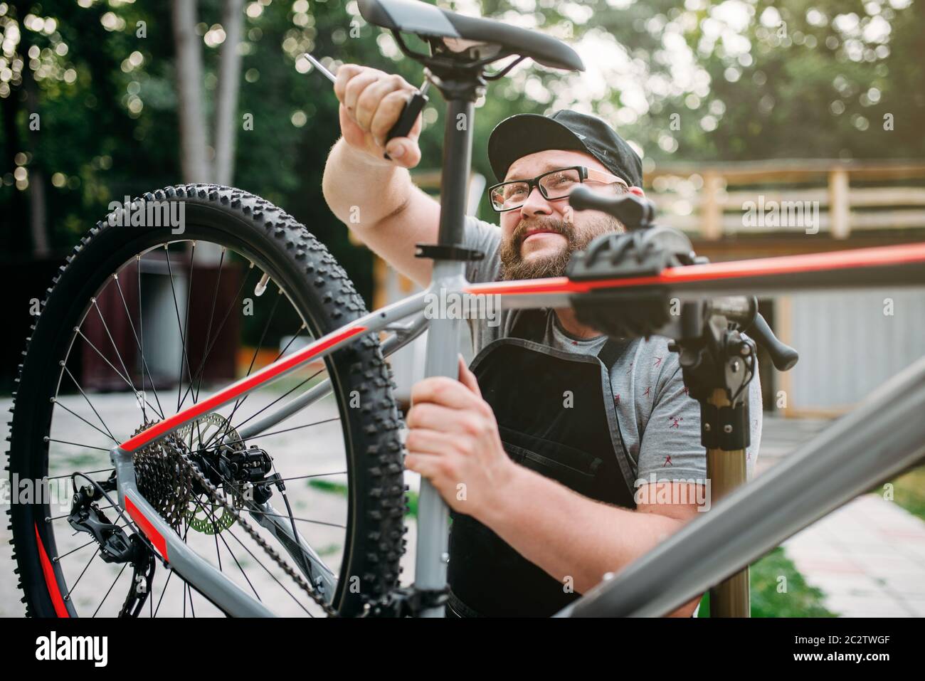 Bicycle mechanic adjusts with service tools bike seat. Cycle workshop ...