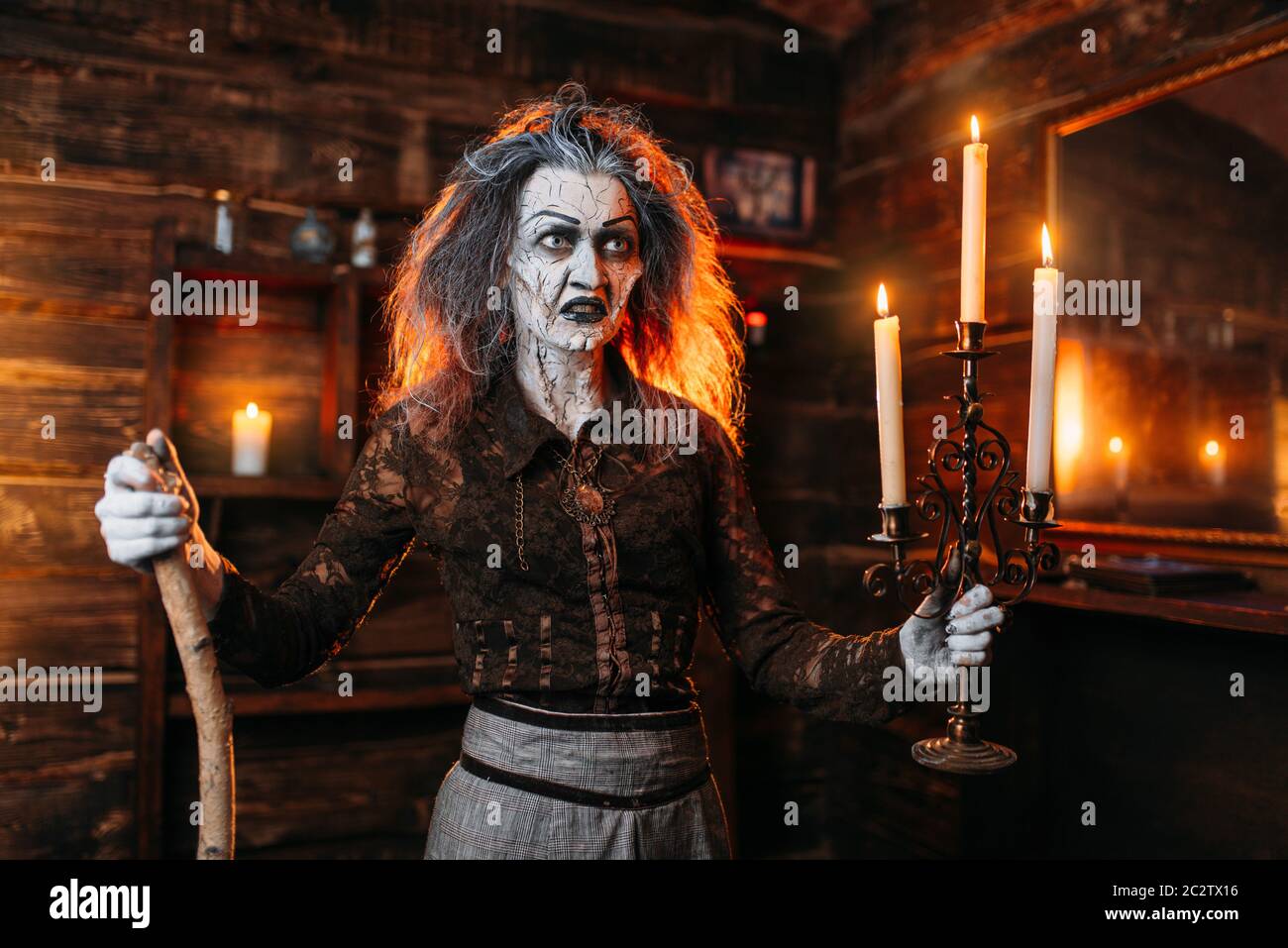 Scary witch with a candlestick and a cane reads mystic spell, spiritual ...