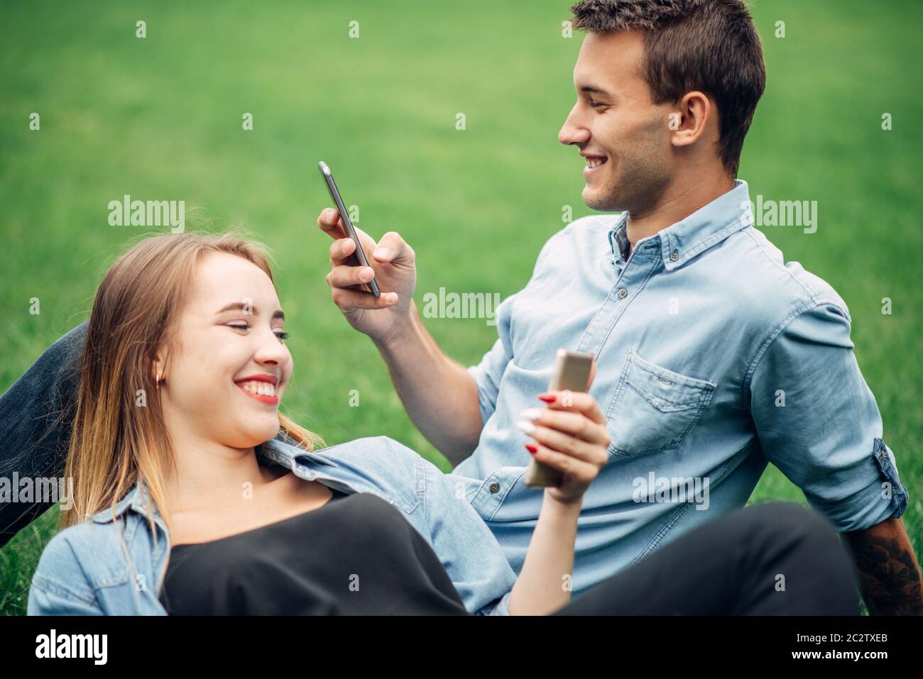 Phone addicted people, couple lies on the grass and using their ...