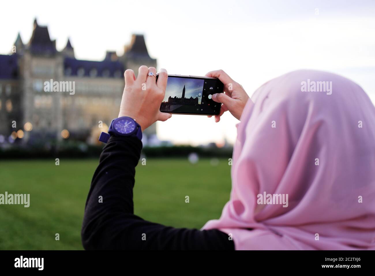 A muslim tourist taking a photo on the parliament hill building using ...