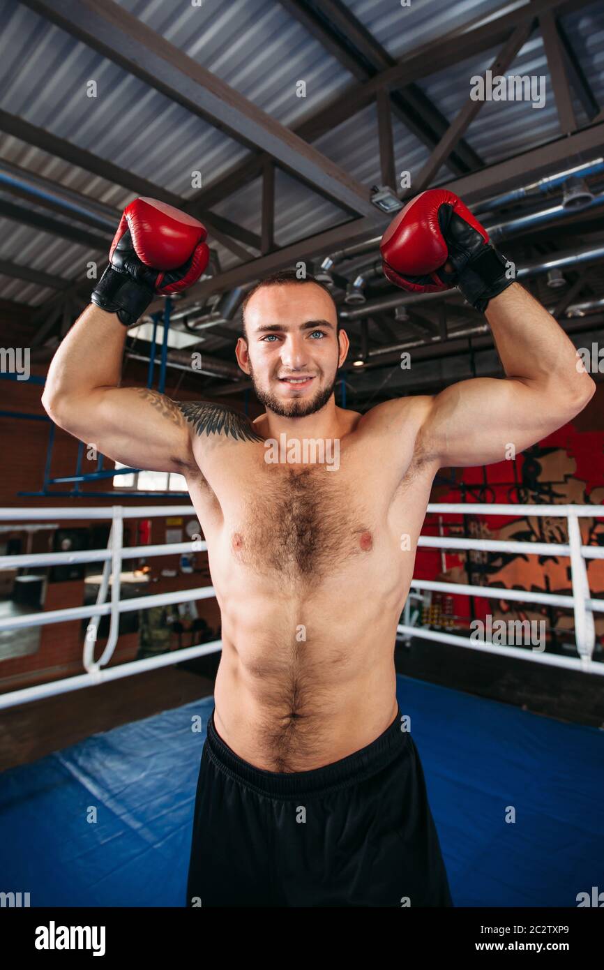 Boxer with an angry face has raised a hand up. Fighting ring on the ...