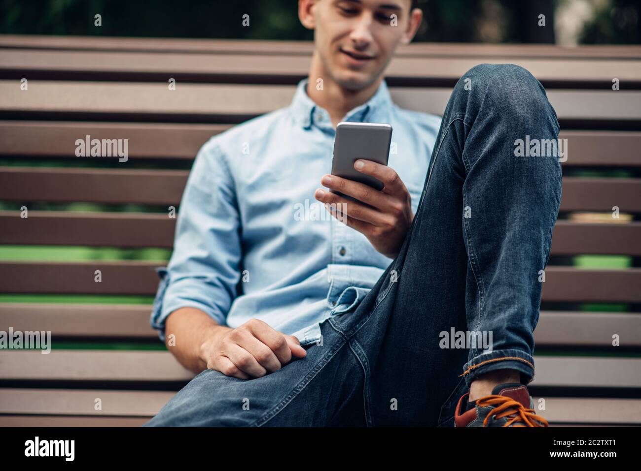 Phone addiction, addict man using smartphone on the bench in park ...