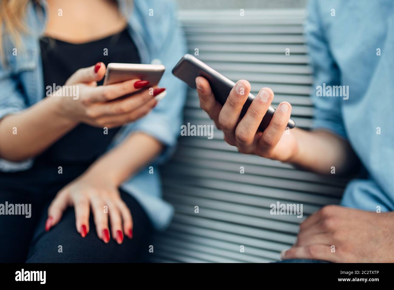 Phone addiction, addict couple sitting on the bench and looking on ...