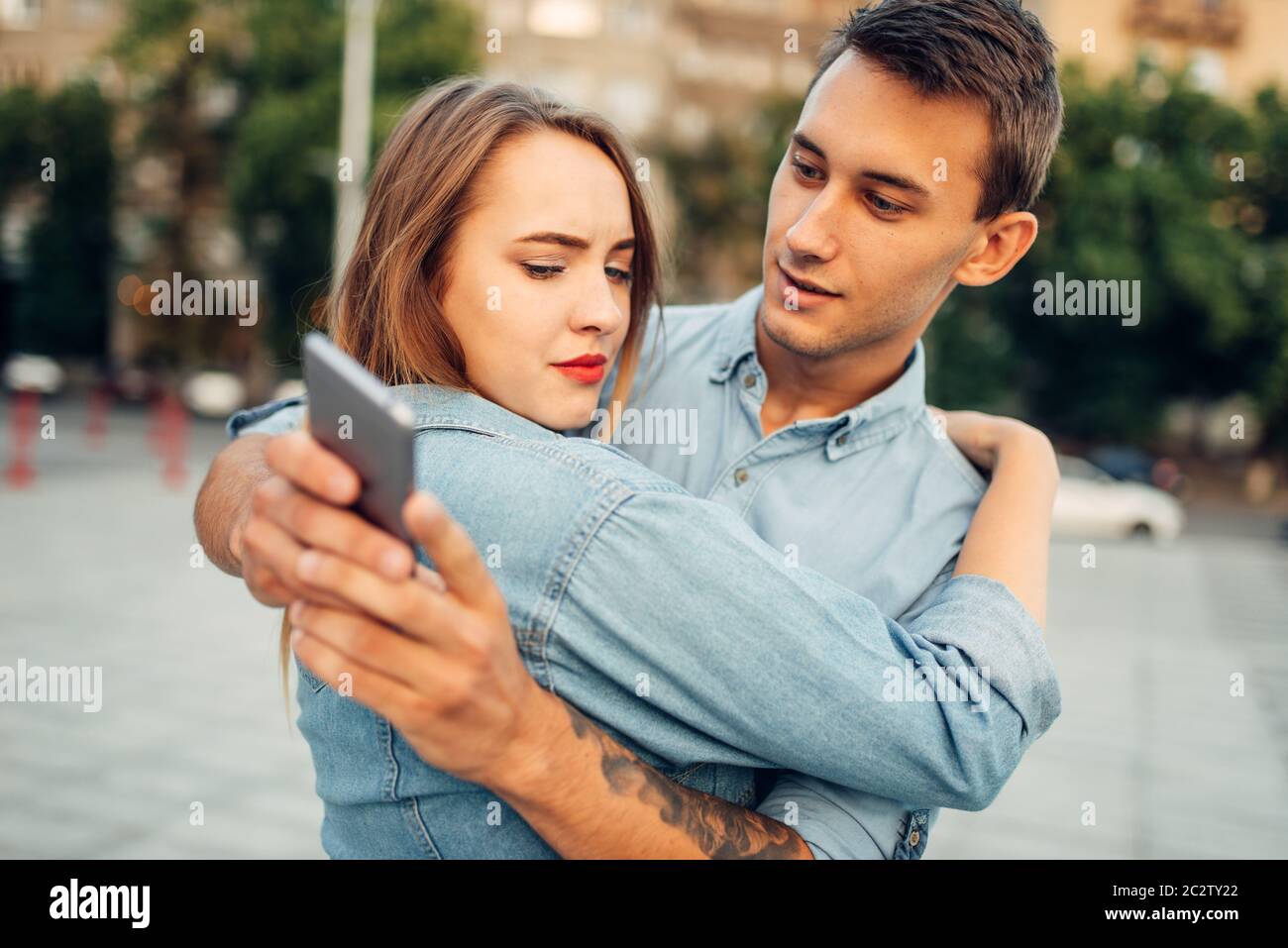 Phone addiction, addict man hugs woman and looking at his gadget at ...
