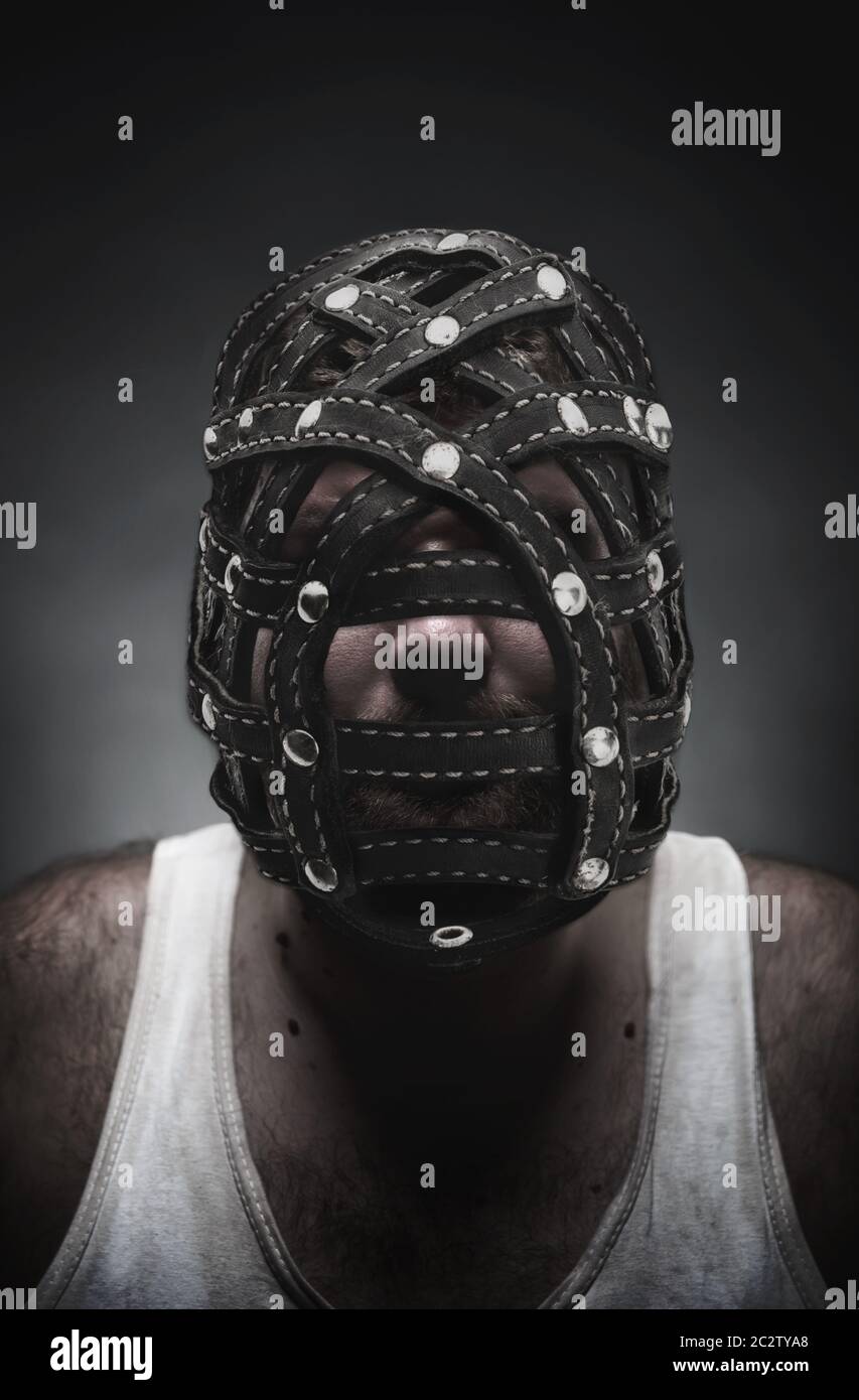 Adult man in muzzle over dark background Stock Photo - Alamy