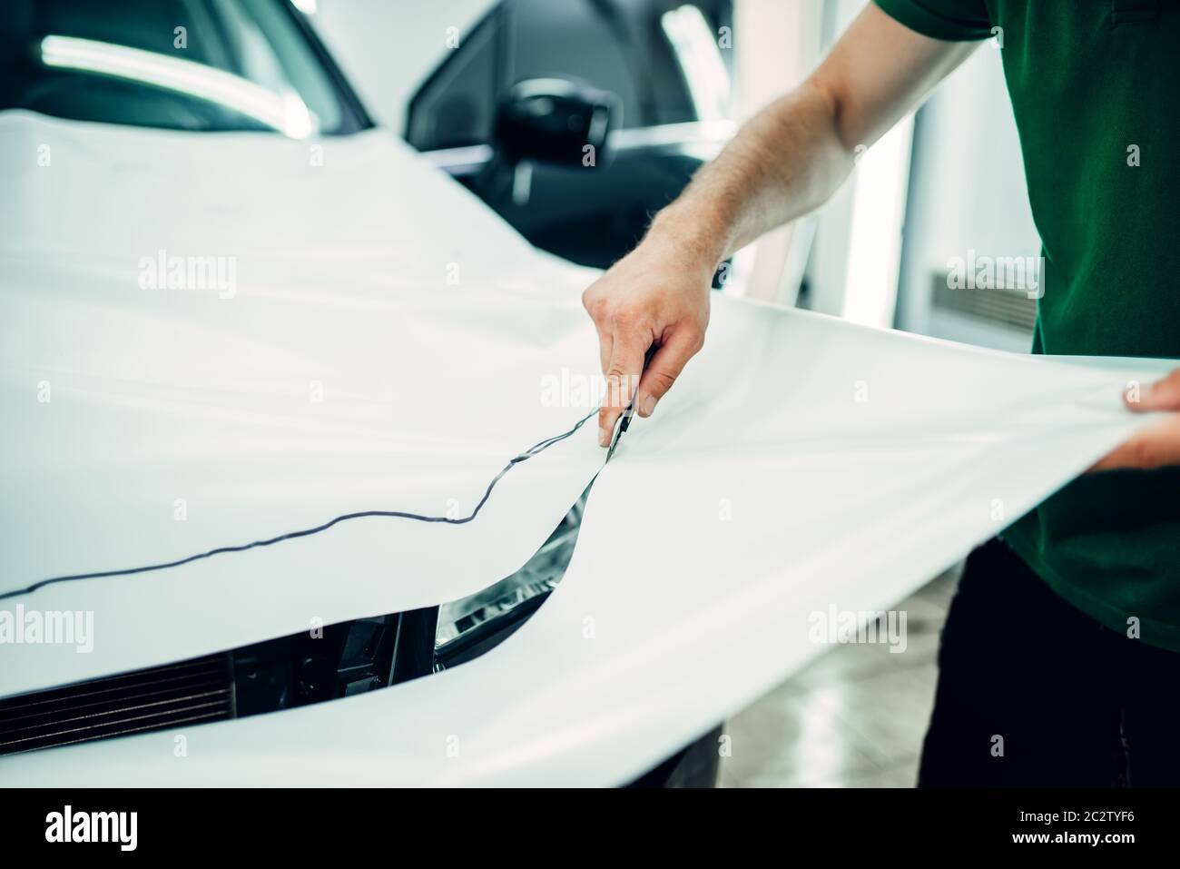 Professional car paint protection film installation process. Worker ...