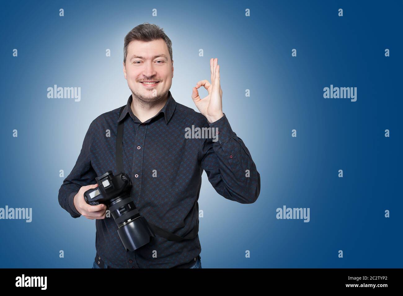 Professional photographer with digital camera shows ok sign, blue ...