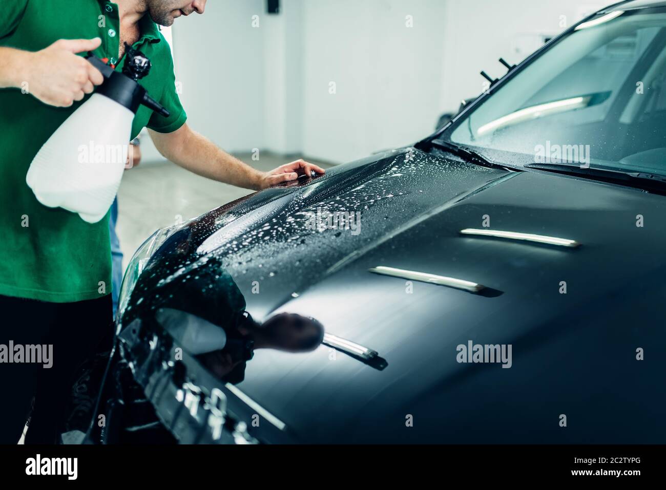 Preparing car, protect against chips and scratches. Worker disperses ...
