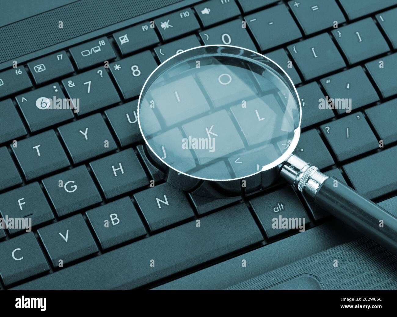 Magnifying glass on laptop computer. Toned in blue Stock Photo - Alamy