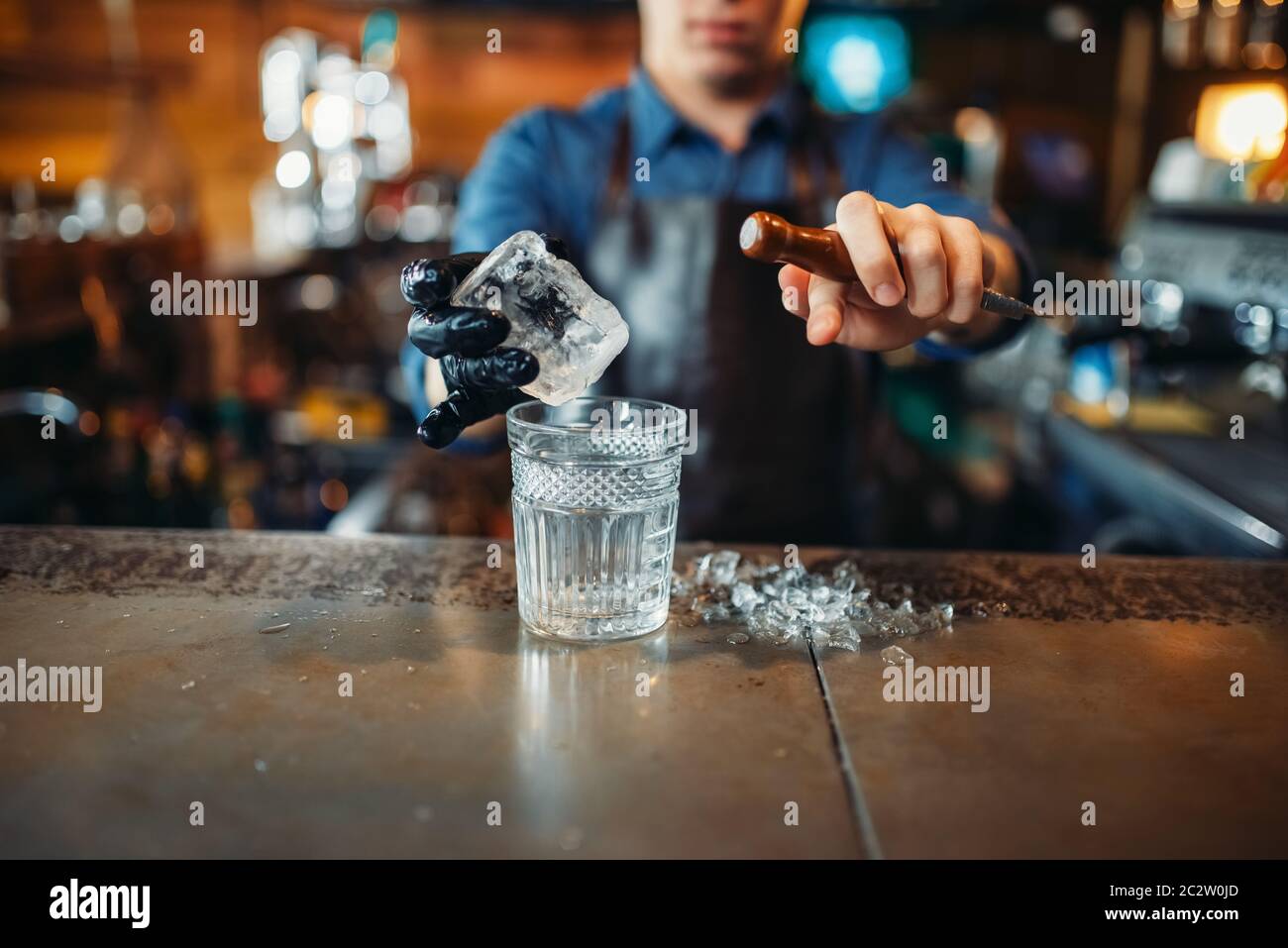 Male bartender pours a drink into a glass with ice. Barman at the bar ...