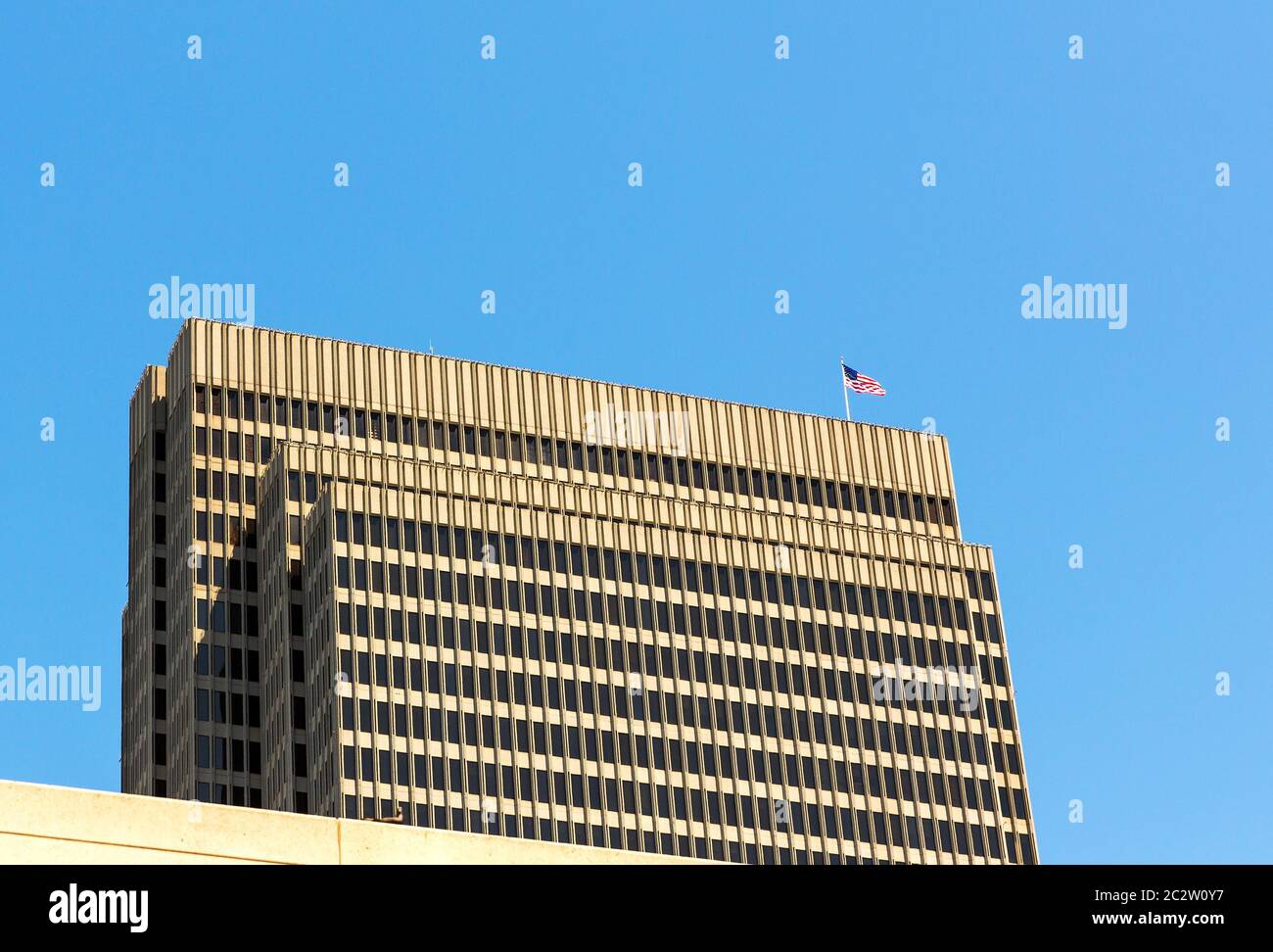 Skyscraper with US flag on roof. Closeup of house top floors and roof ...