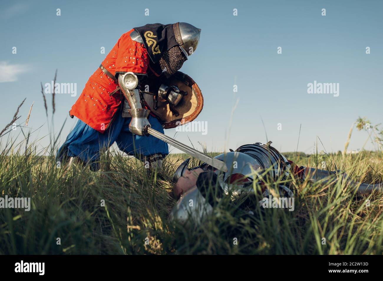 Medieval knight in armor and helmets put his sword to his opponent's ...