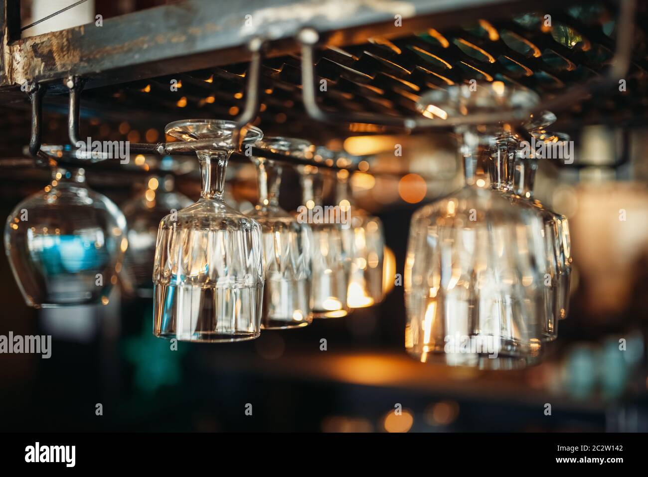 Row of glasses hanging on the bar counter closeup, nobody. Barman ...