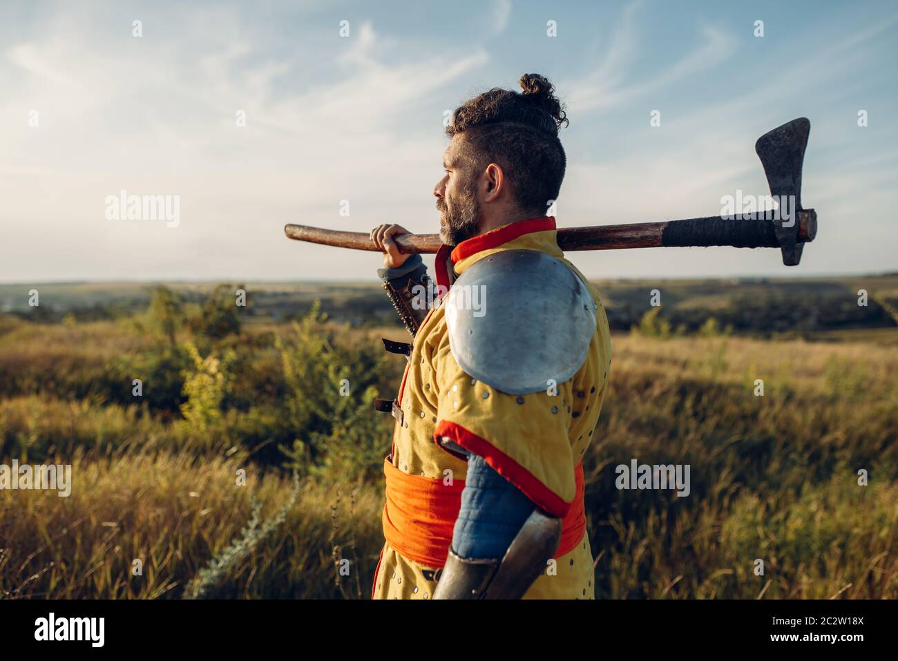 Medieval knight with axe poses in armor opposite the castle, great ...