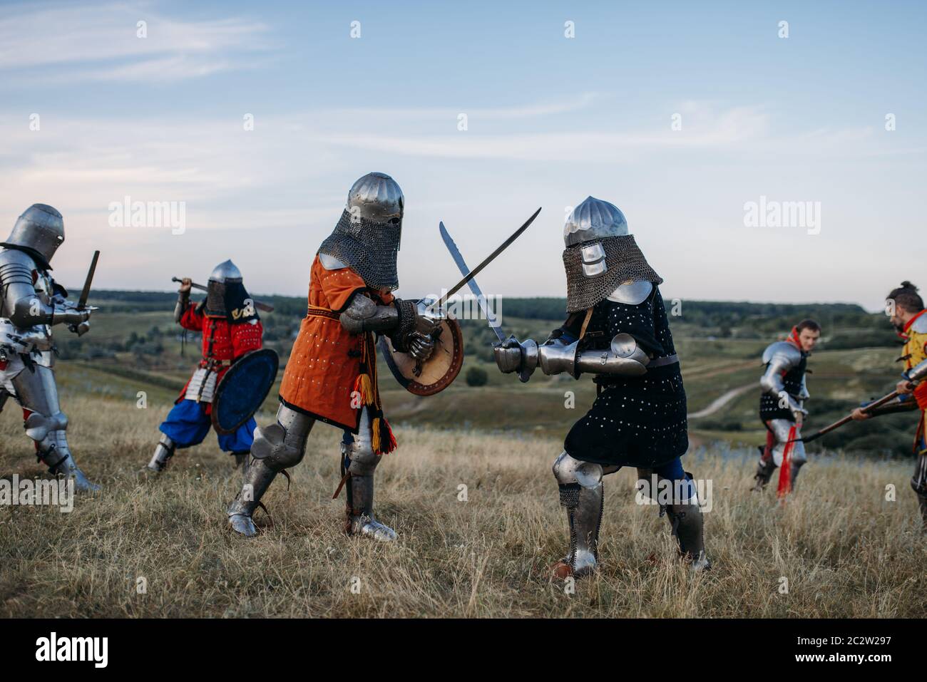 Medieval knights in armour and helmets fight with swords. Armored ...