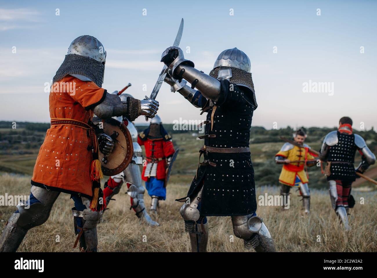 Medieval knights in armour and helmets fight with swords. Armored ...