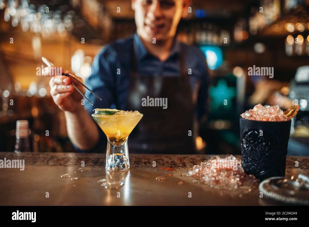 Male barman making coctail with the help of forceps. Barkeeper ...