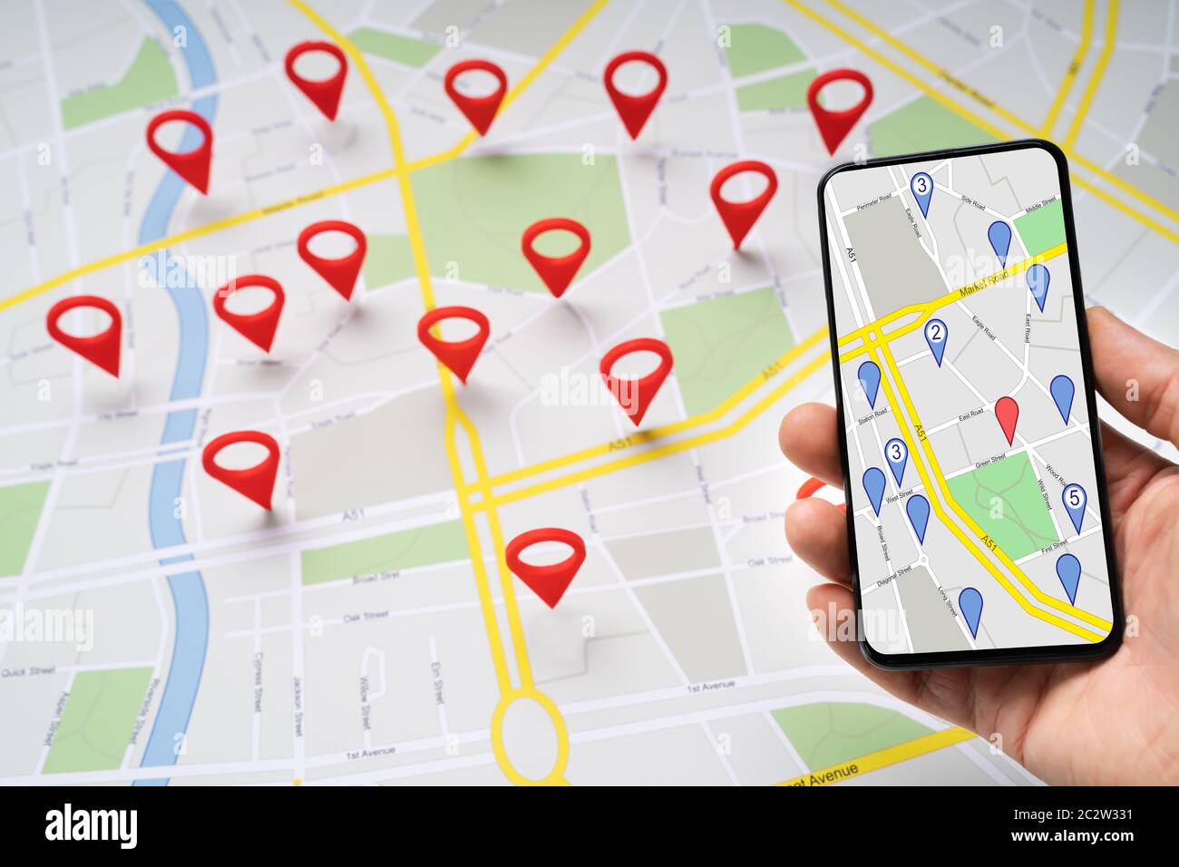 Person's Hand Holding Mobile Phone Against Road Map With Red Navigation ...