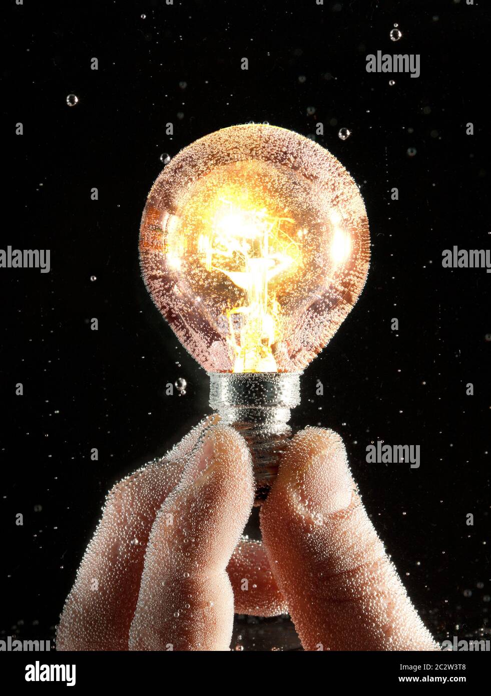 Hand holding turned-on conventional bulb under water Stock Photo - Alamy