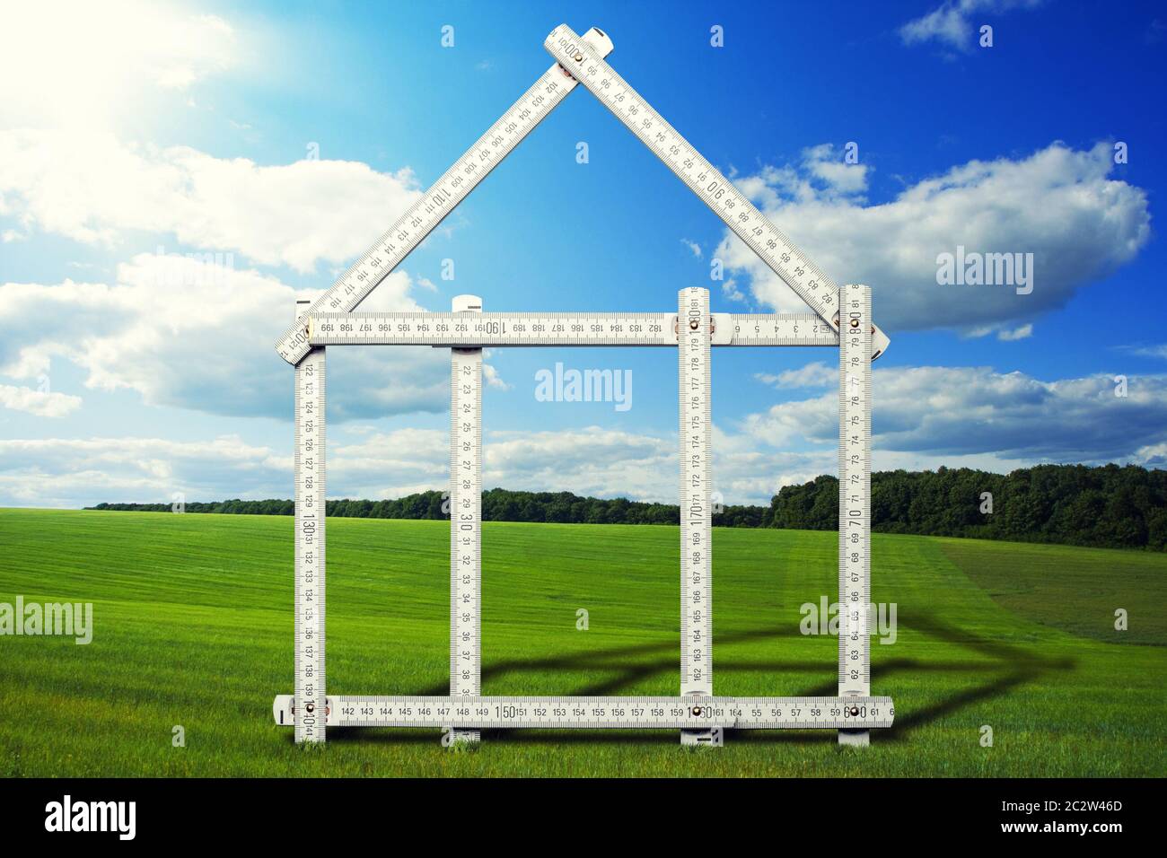Wooden ruler make a house symbol on meadow Stock Photo - Alamy