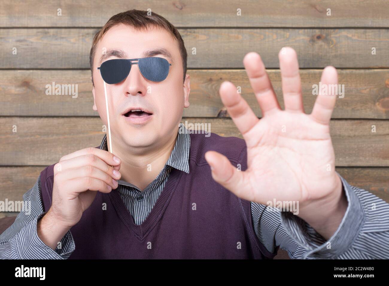 Playful man with funny sunglasses on a stick represents the blind ...