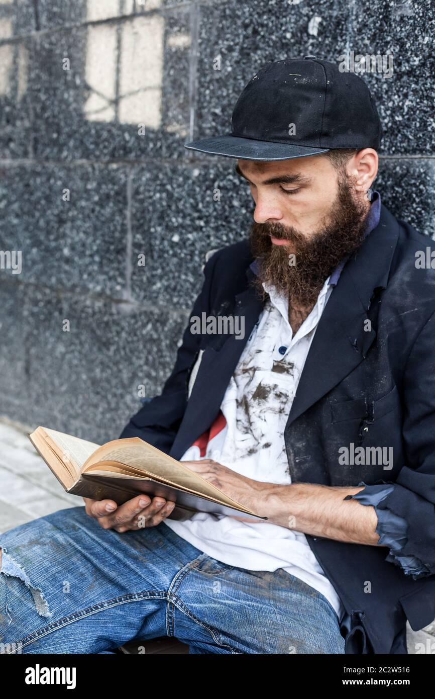 Homeless is reading sitting outdoor Stock Photo - Alamy