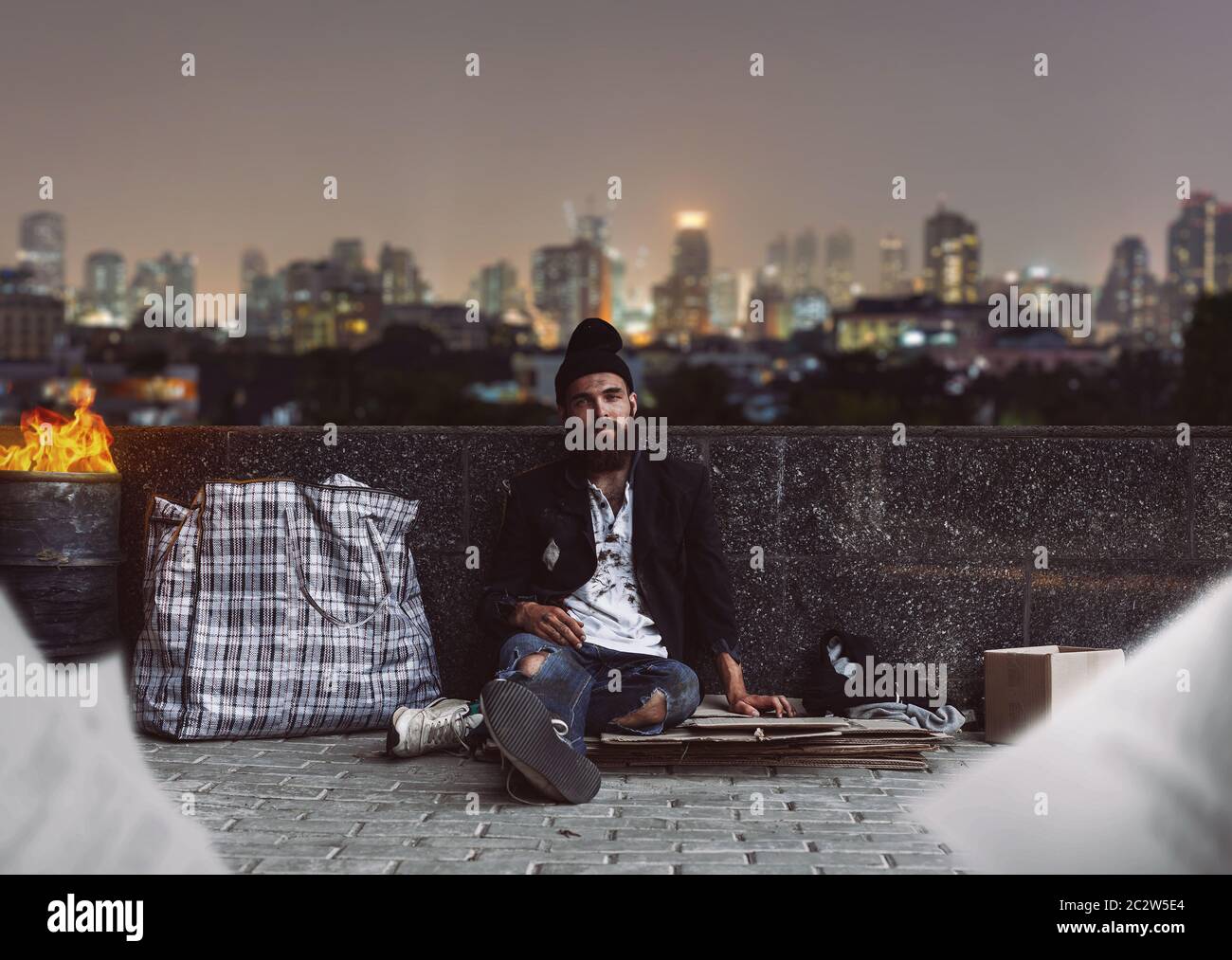 Dirty homeless sitting on the cardboard with his stuff Stock Photo - Alamy