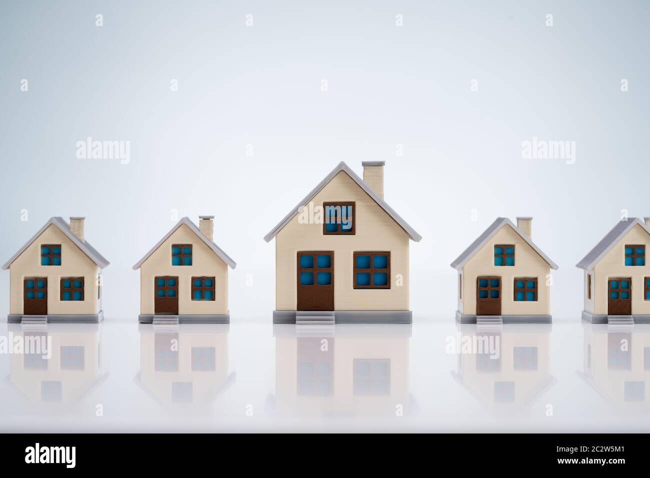 Small Beautiful House Models Arrange In A Row Over Reflective Table ...