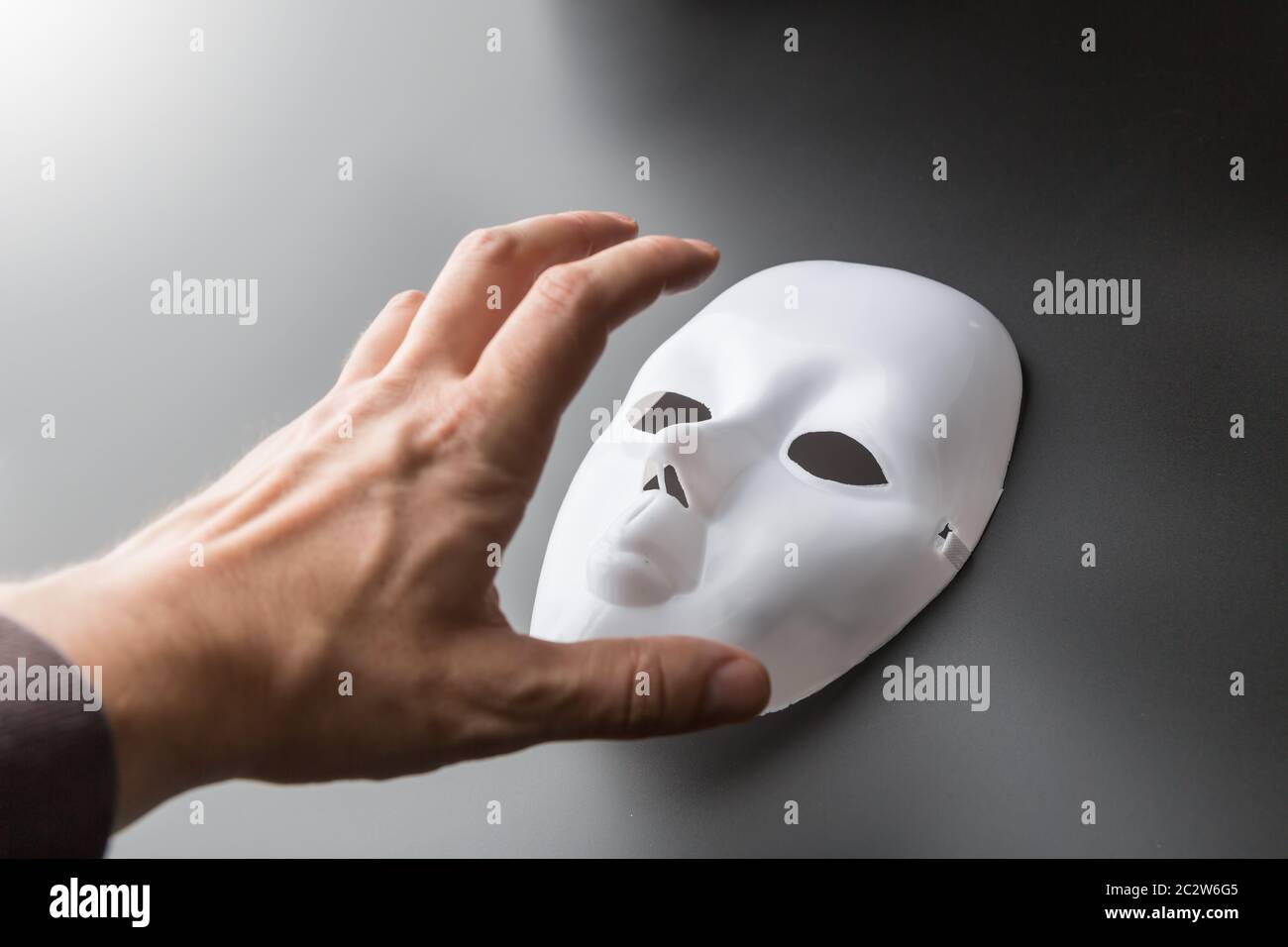Human hand tries to take theater mask on grey background Stock Photo ...