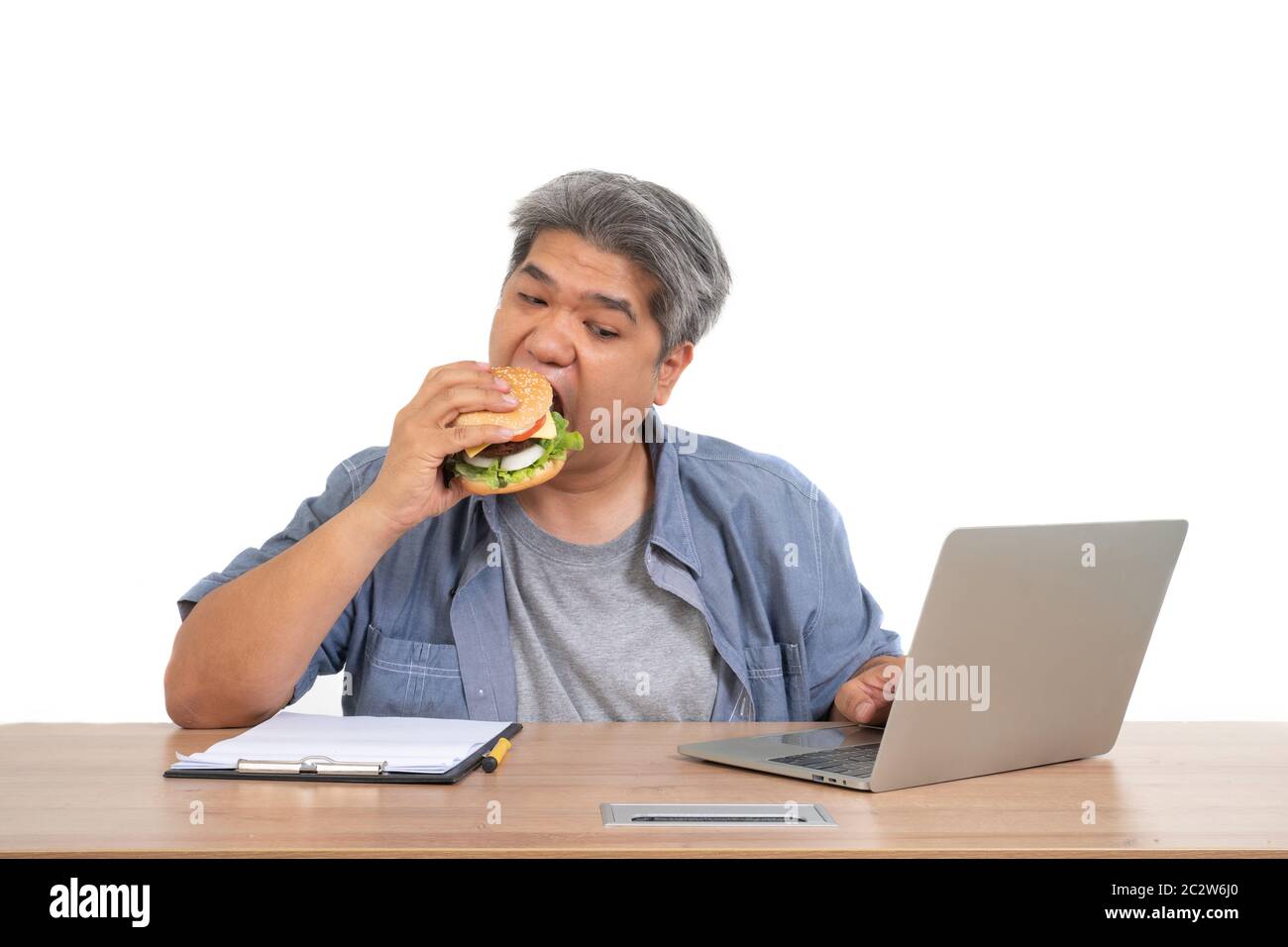 Asian man working and eating a burger on the office desk. Concept of a ...